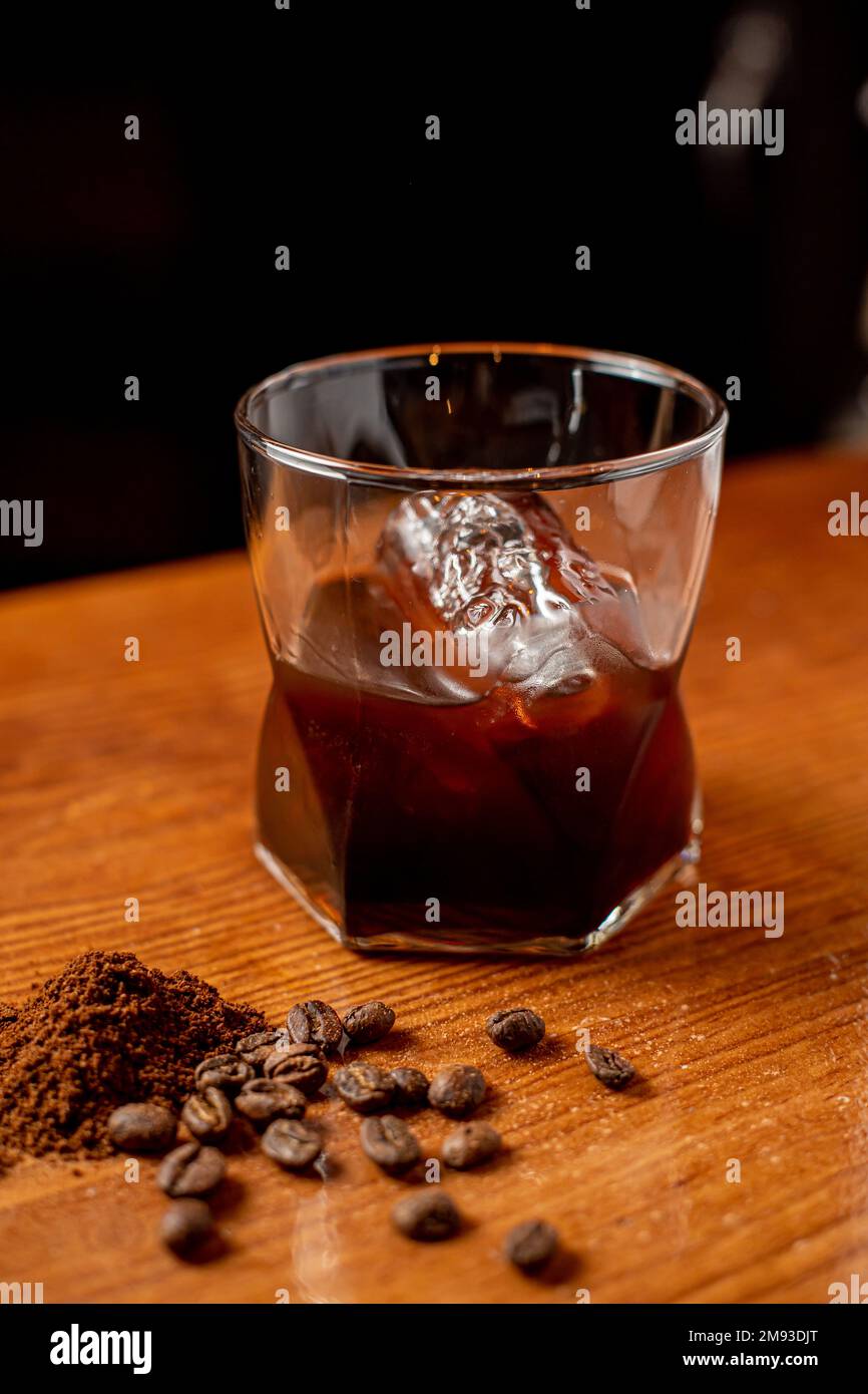 A vertical closeup of a refreshing iced coffee in a glass next to ...