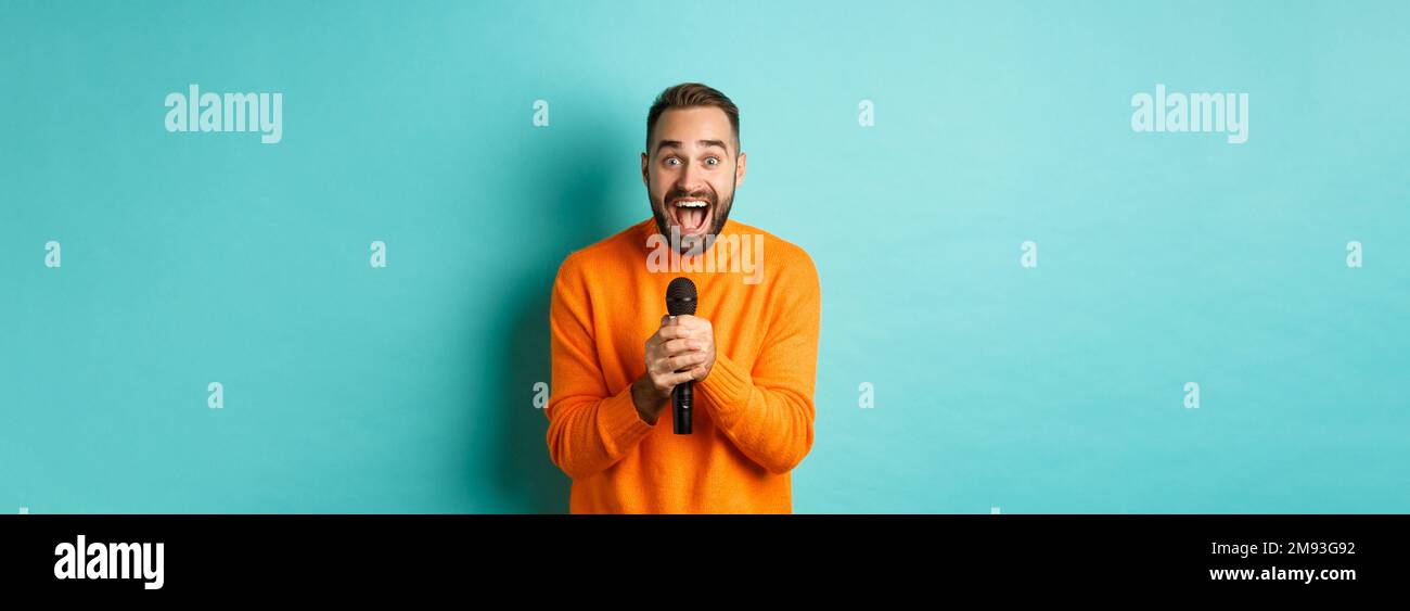 Handsome adult man perform song, singing into microphone, standing ...