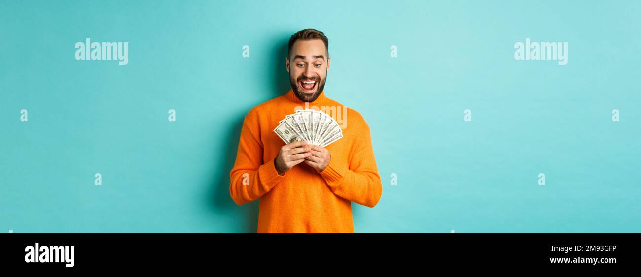 Image of man looking happy at money, smiling amazed, standing over ...