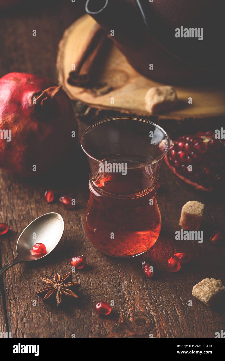 Black tea in arabic tea glass with pomegranate seeds and some spices on ...