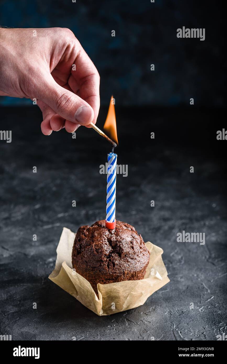 Hand lighting candle with a match on birthday chocolate muffin Stock ...
