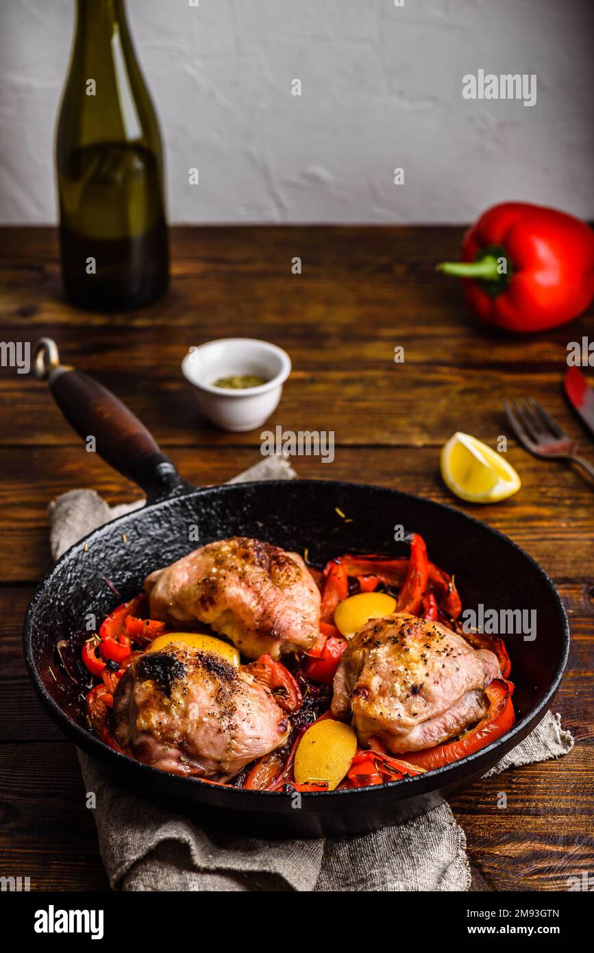 Chicken thighs baked with red bell peppers, rosemary and lemon in cast ...