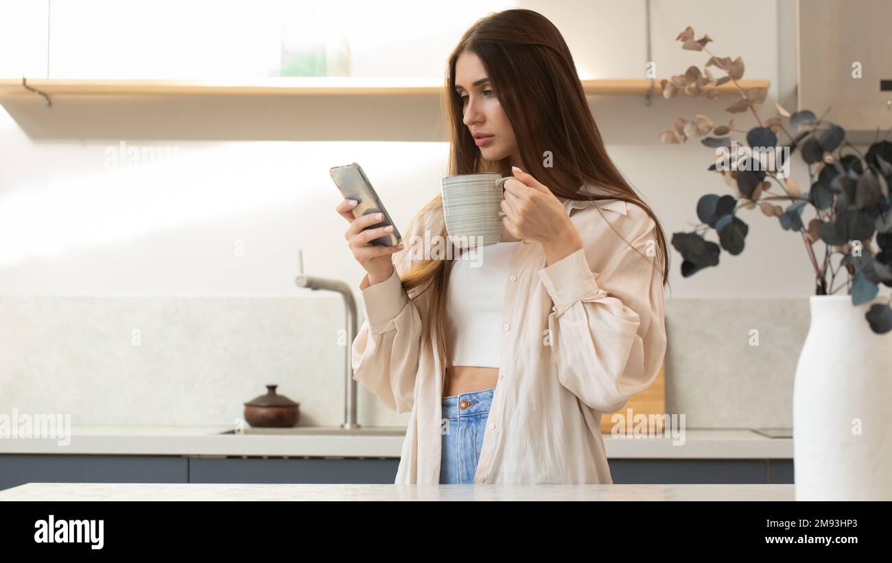 A young brunette woman uses her phone while making online purchases ...
