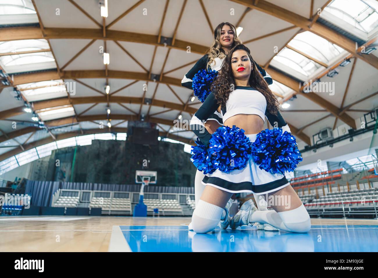 Low angle shot of a kneeling cheerleader with another one standing ...