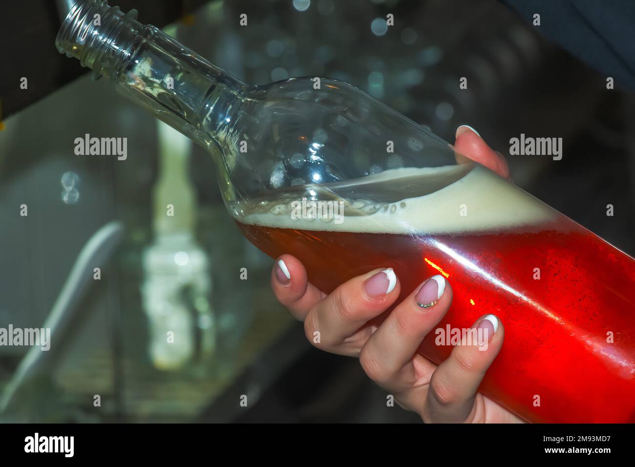 The hand of a bartender girl at a beer tap pours draft beer into a ...