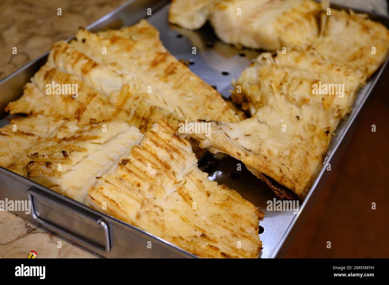 Cod fish salted bacalhau grilled on olive wood firewood grill in small ...