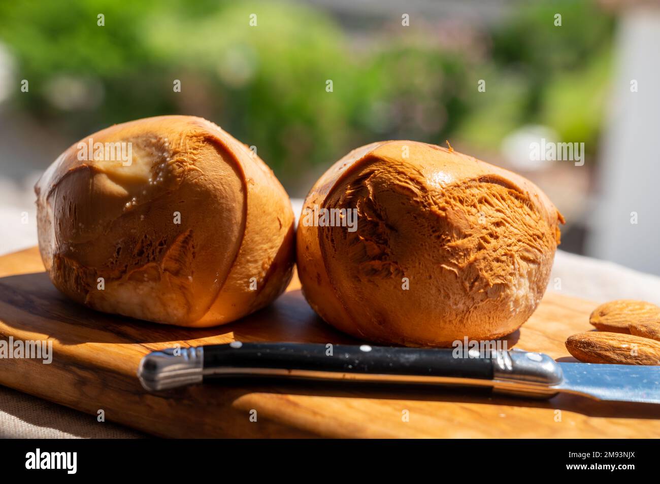 Italian yellow smoked cheese scamorza served on olive tree wooden plank ...