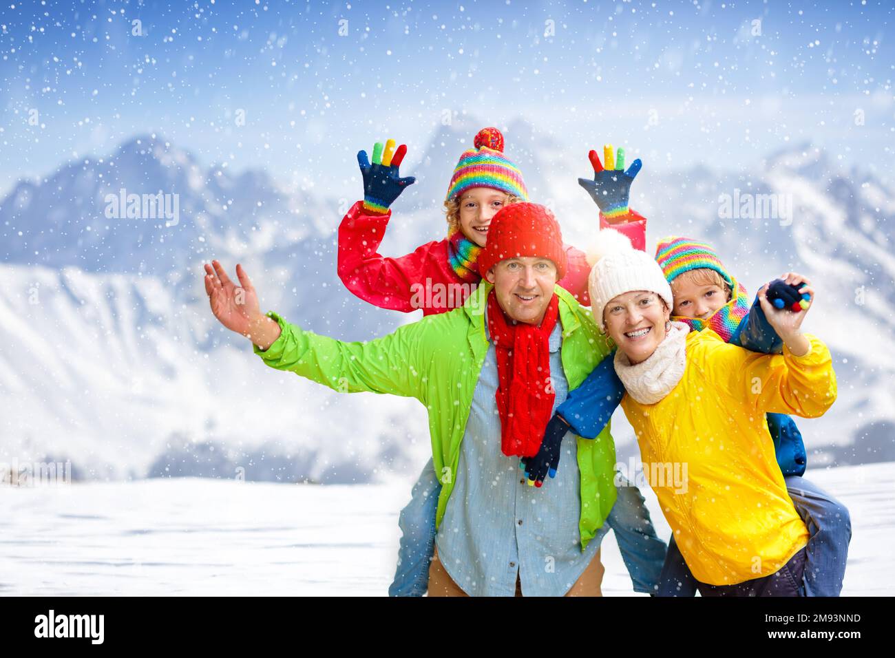 Family in winter mountain resort. Snow and ski fun with kids. Mother, father and children play ...