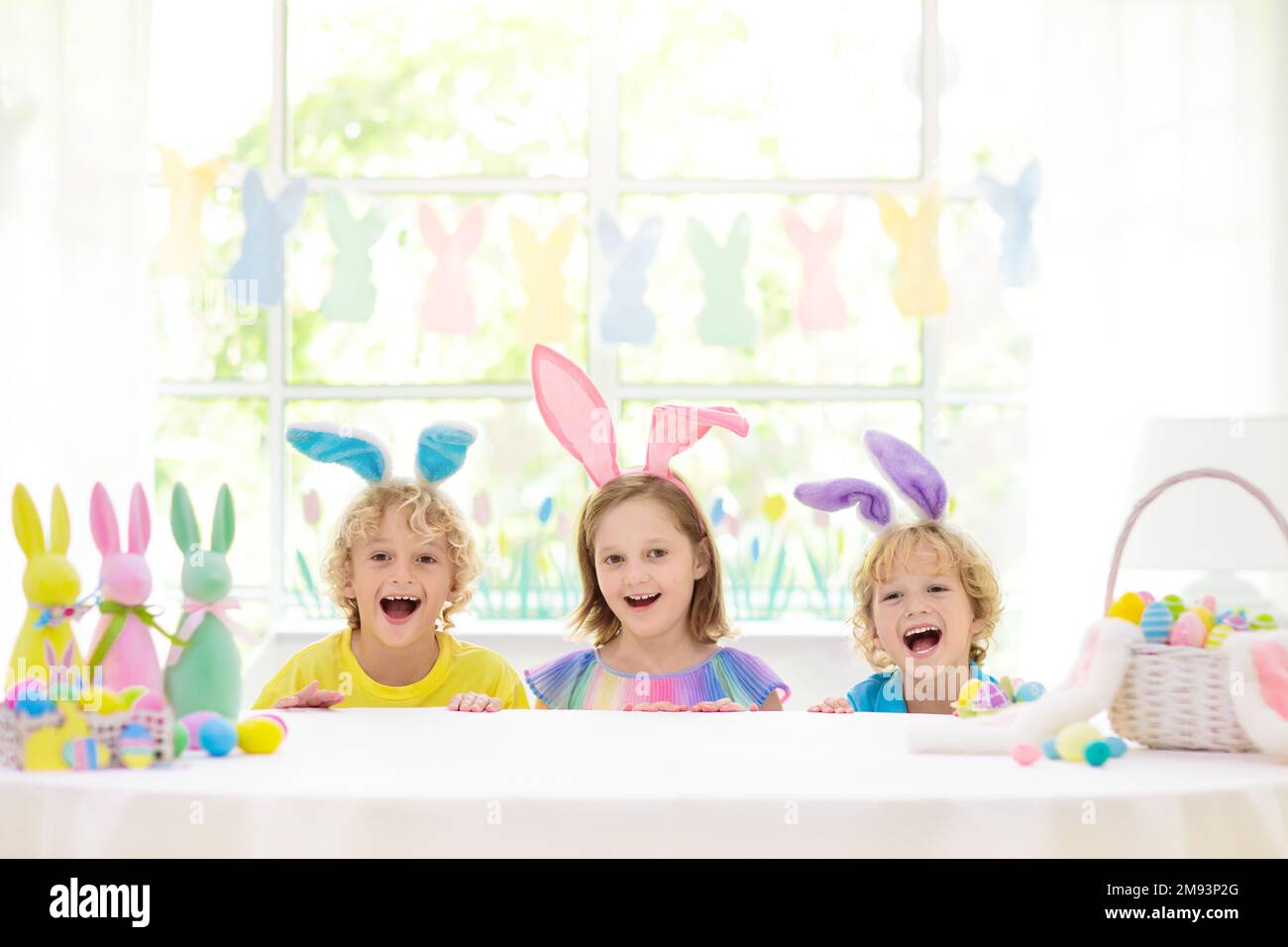 Kids dyeing Easter eggs. Children in bunny ears dye colorful egg for ...