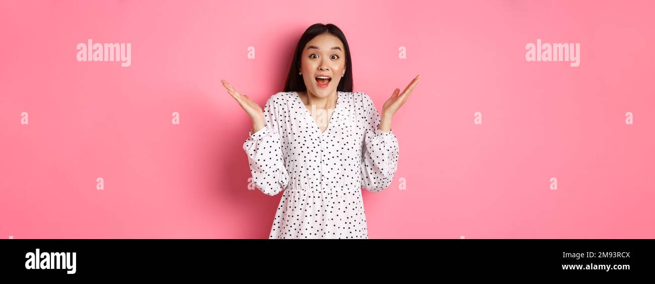Happy and surprised asian woman rejoicing, spread hands and gasping ...