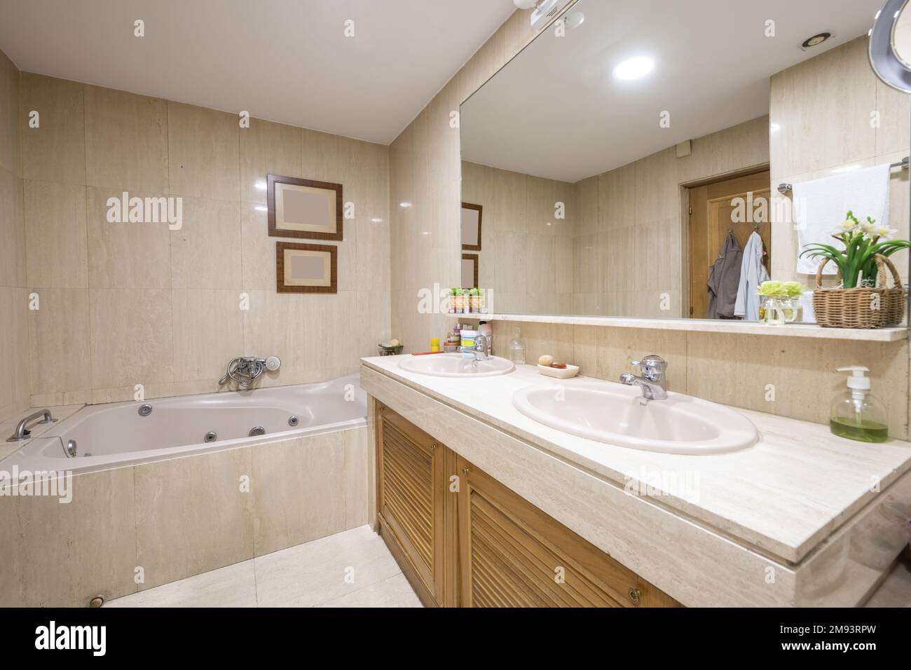 Bathroom with hydromassage bathtub with marble tiles, two sinks on the ...