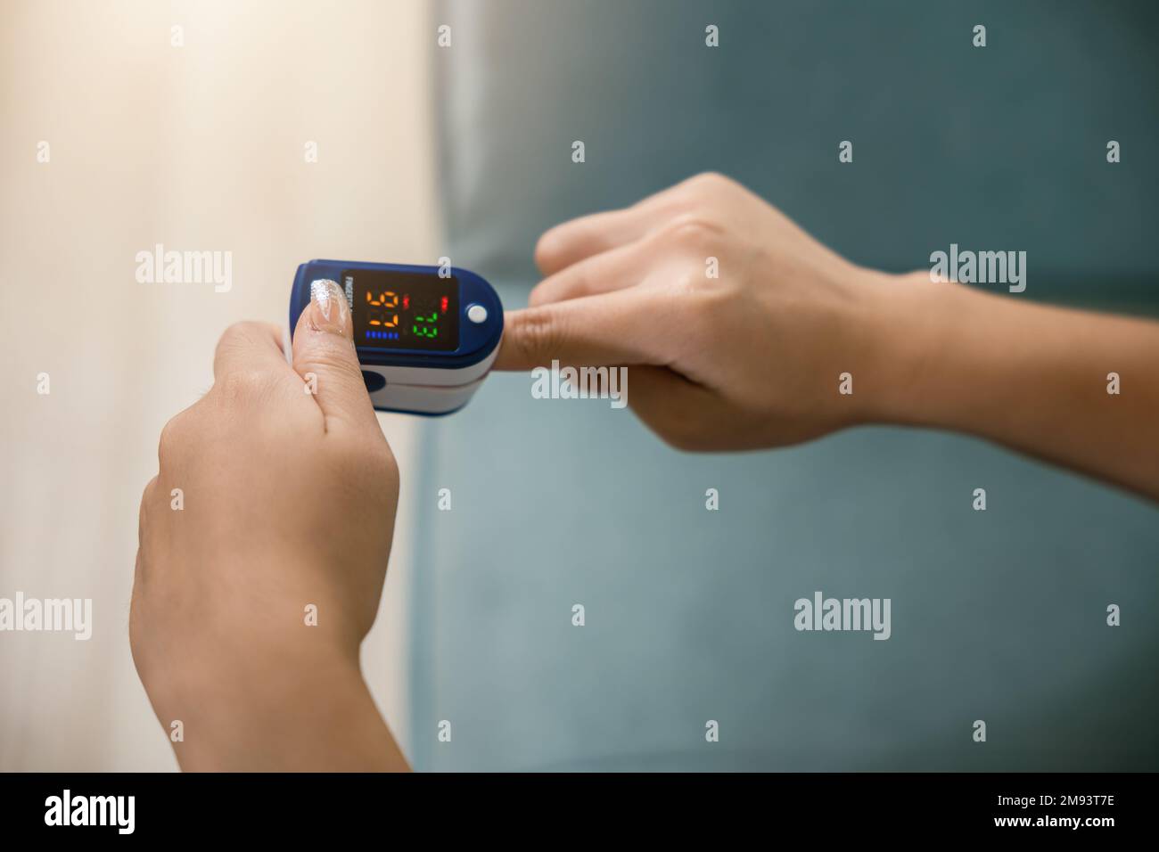 Young woman using pulse oximeter to monitor blood oxygen levels and ...
