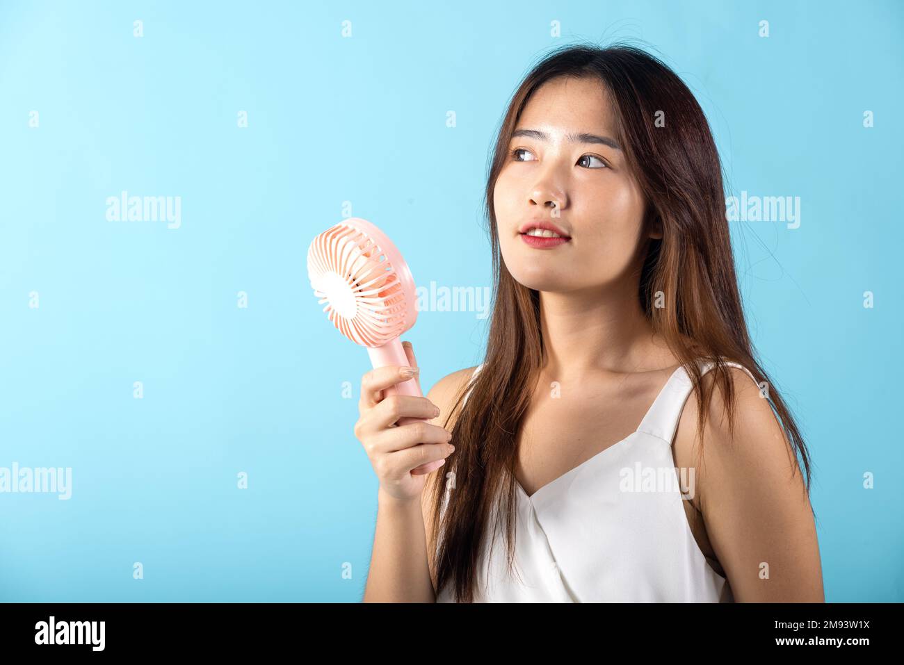 Asian beauty young woman holding pink portable electric mini fan near ...