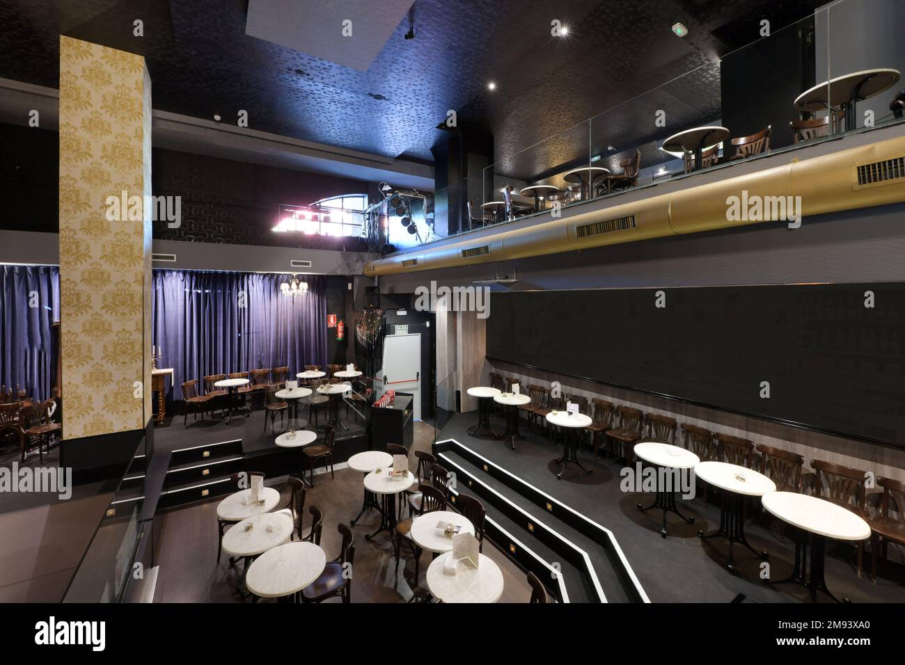 Cabaret theater type venue with two heights and round white tables with ...