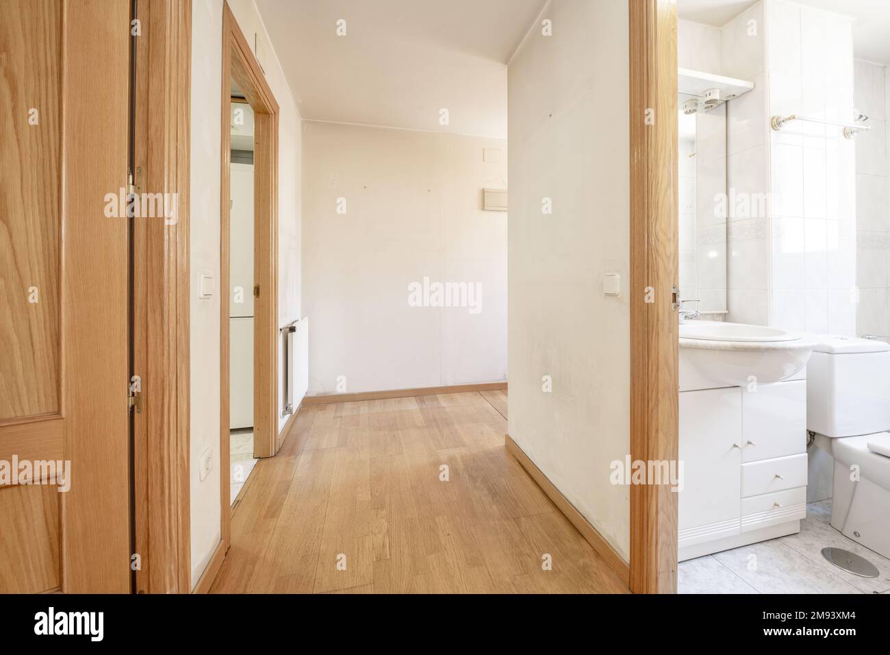 Long narrow hallway with several oak doors and a wooden border along ...