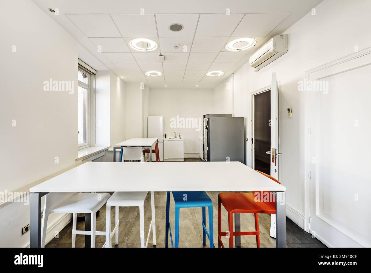 Shared dining room of an office with high tables with colored stools ...