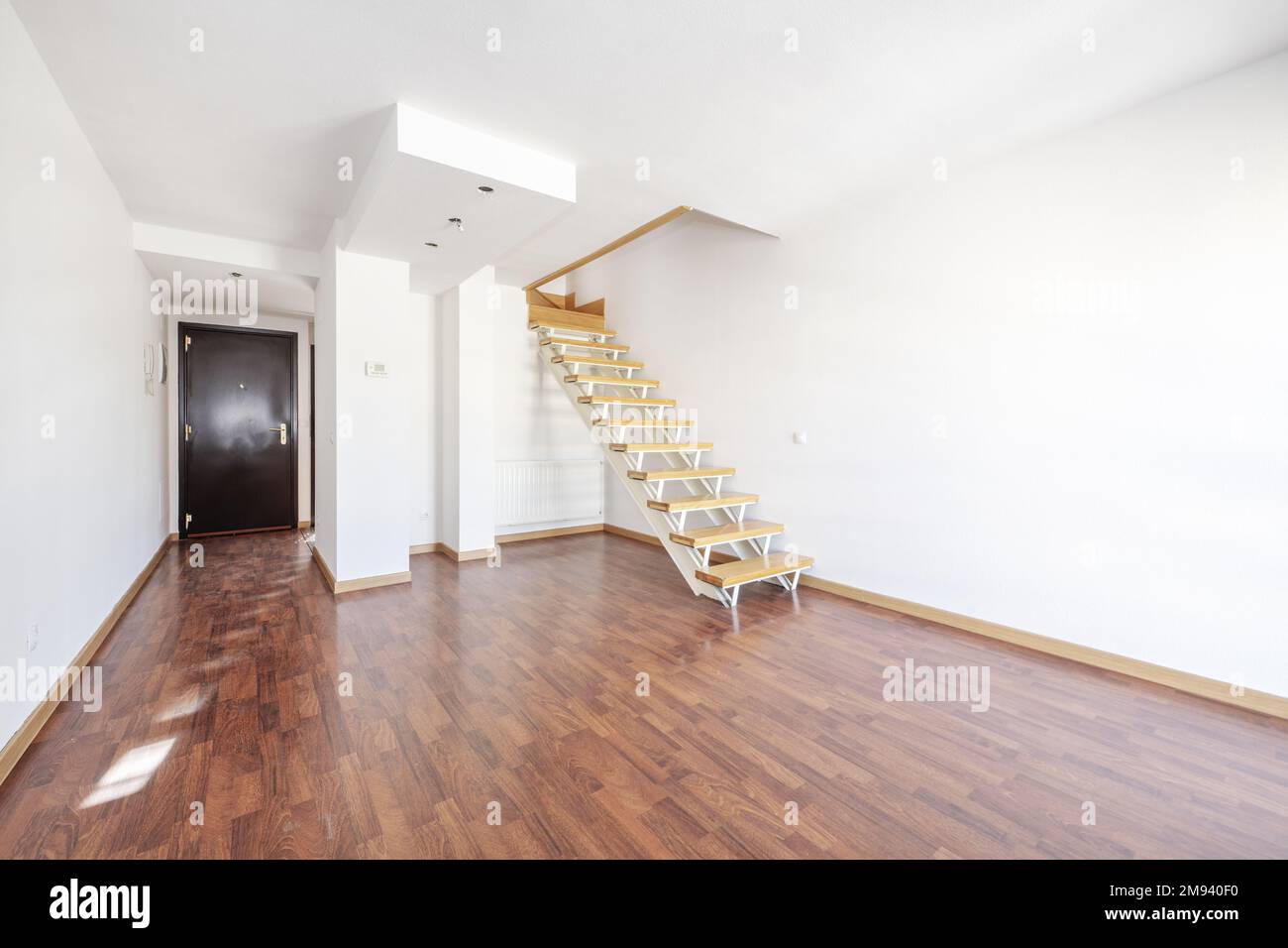 Empty room of a two-story loft apartment with a white metal staircase ...