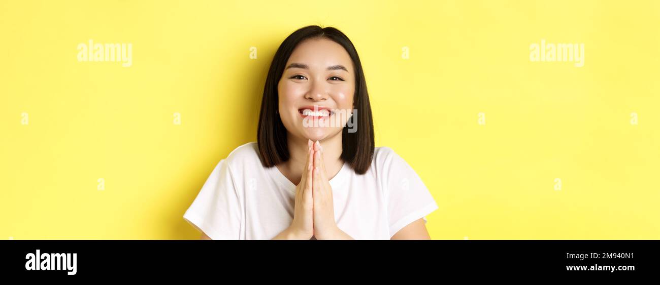 Close up of cute asian woman saying thank you and smiling, holding ...