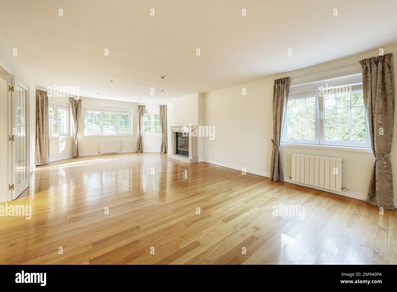Large empty living room with marble fireplace, aluminum radiators and ...
