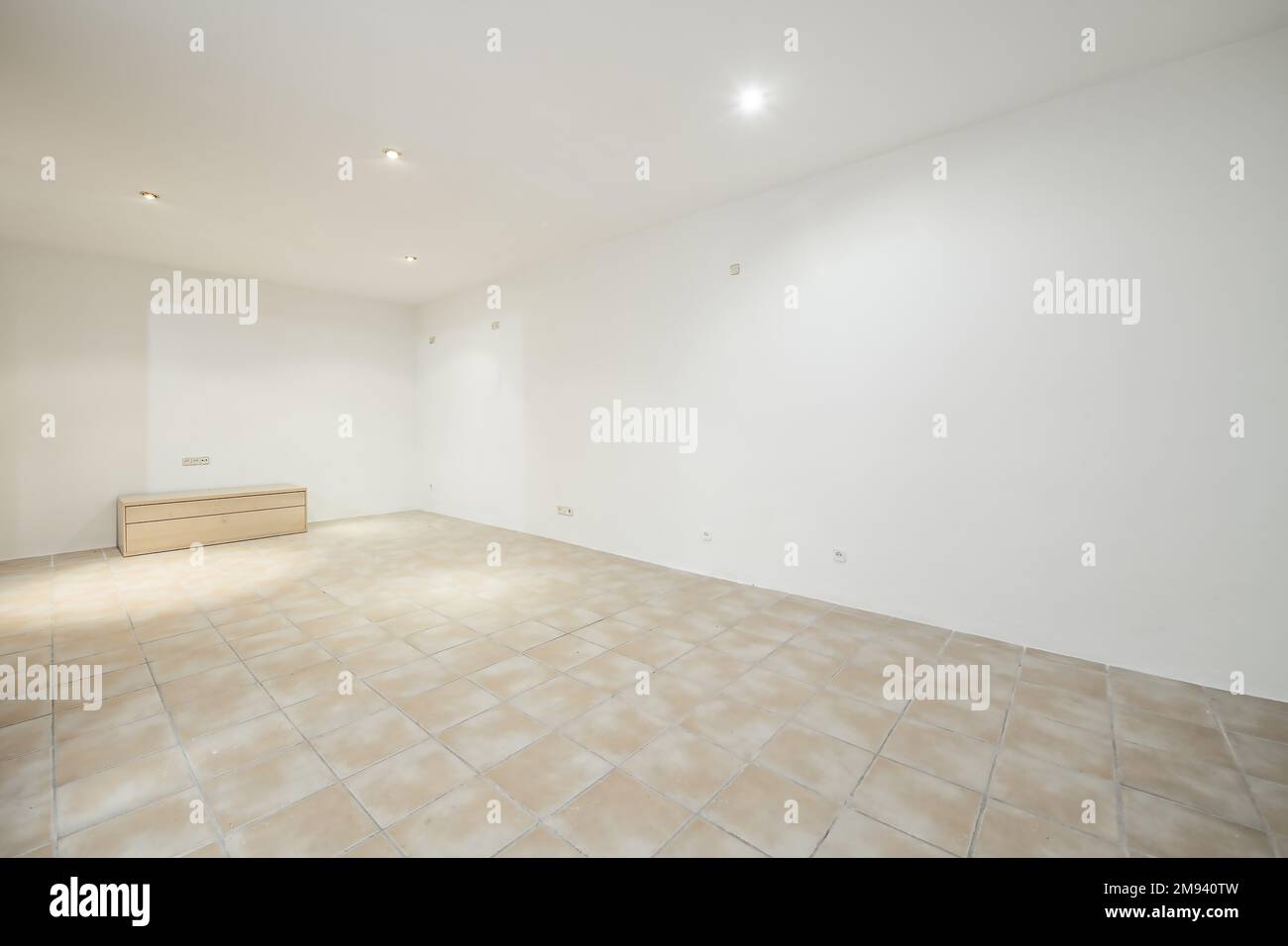 Empty room with plain white walls with light brown square tiles and ...