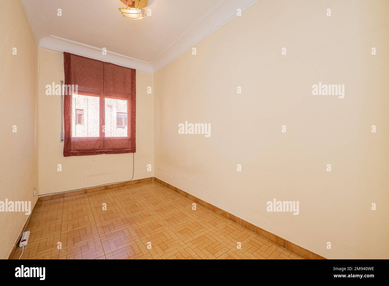 Empty room with plain cream painted wall with tiled floor and single ...