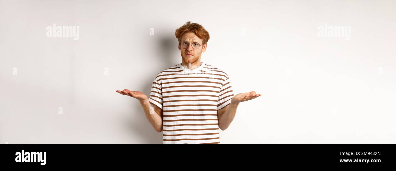 Confused boyfriend with red hair shrugging, spread hands sideways and ...