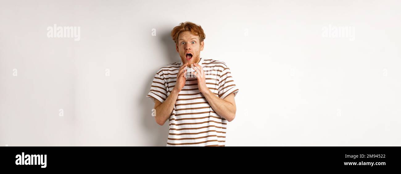 Timid young man with red hair, looking scared, jumping and screaming ...