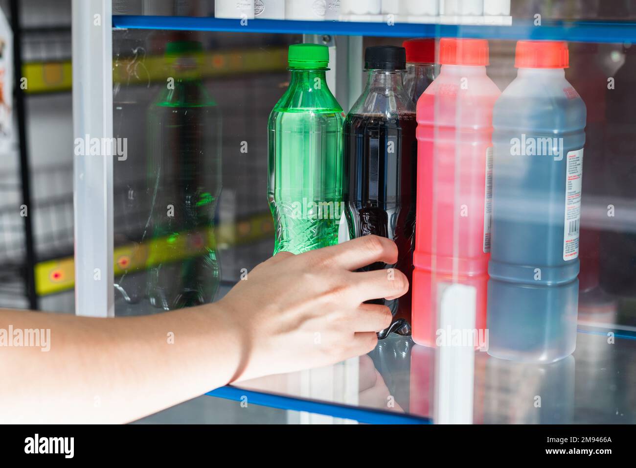 hand of a girl holding a sugary soda, taking it out of a glass display ...