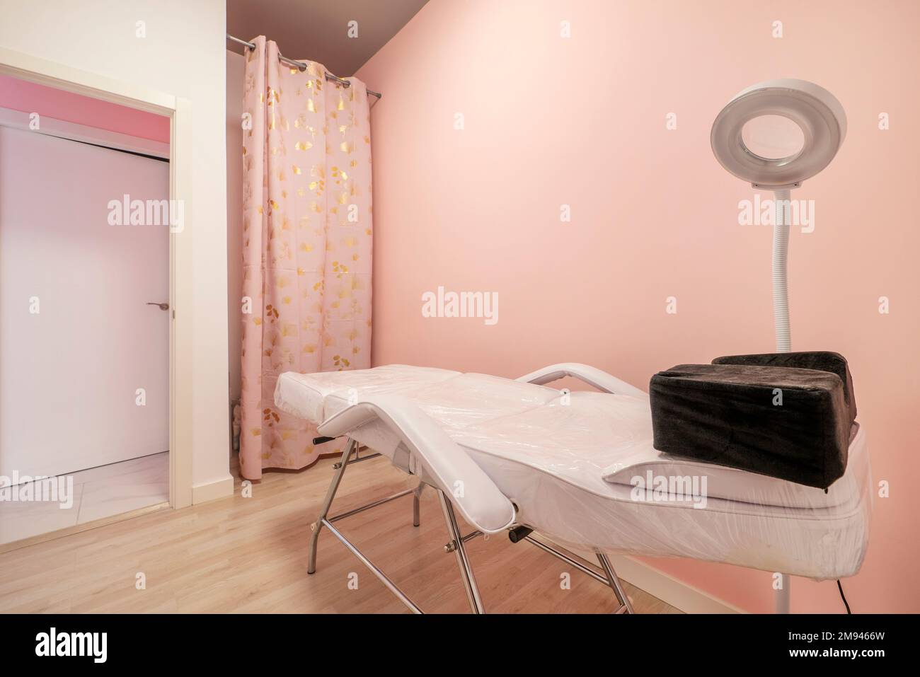 Massage booth with a folding table in a beauty salon with pink walls, a ...
