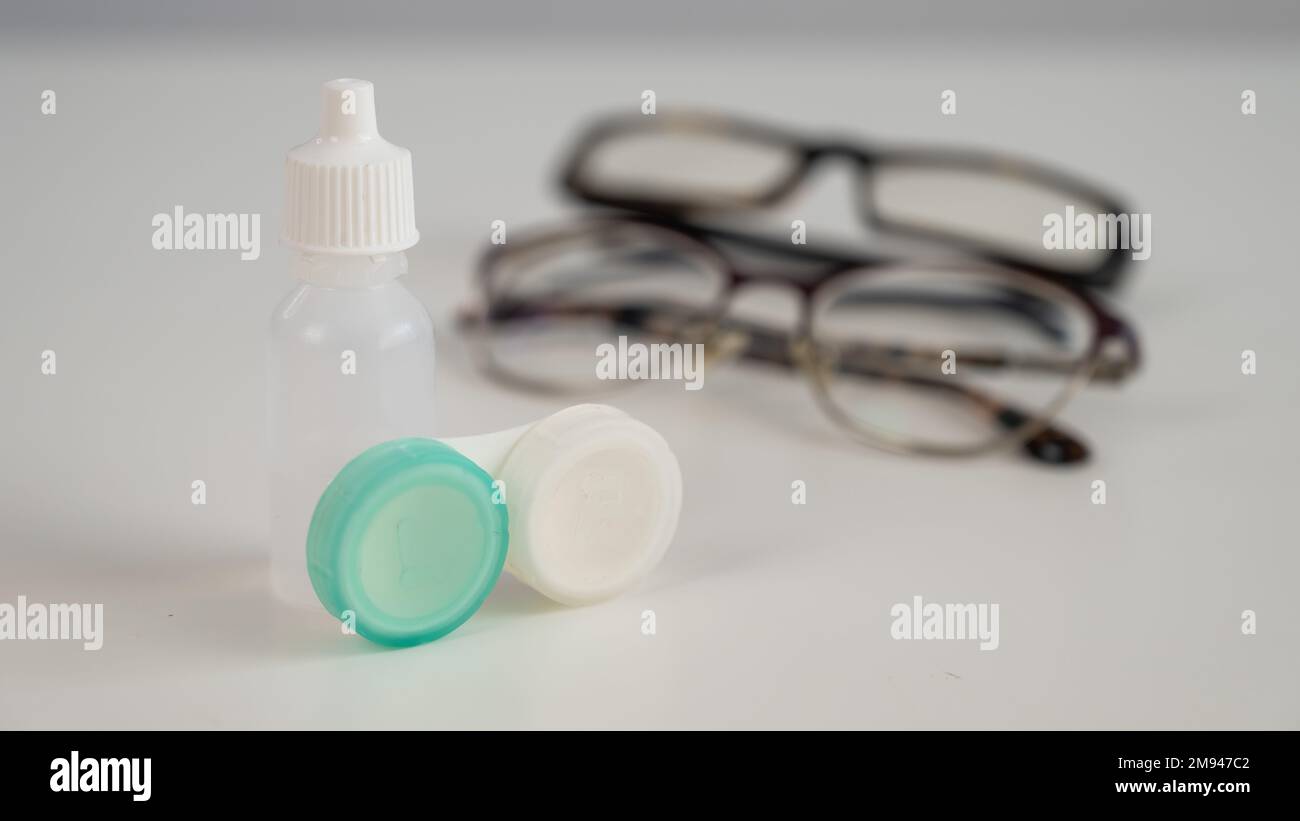 Two pairs of glasses lenses and contact drops in the eyes on a white ...