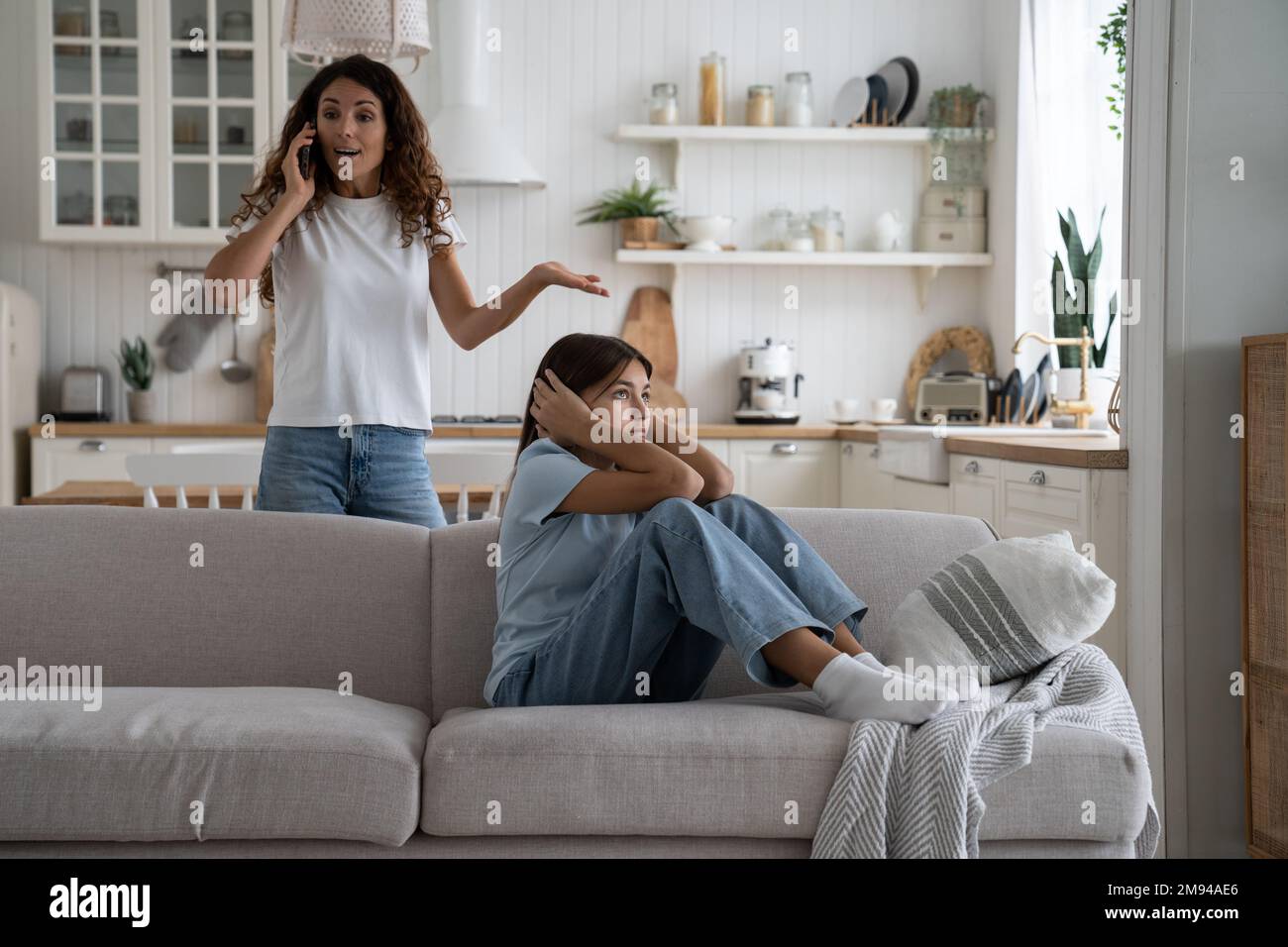 Angry strict woman mother holding smartphone talking with husband complaining about teenage ...