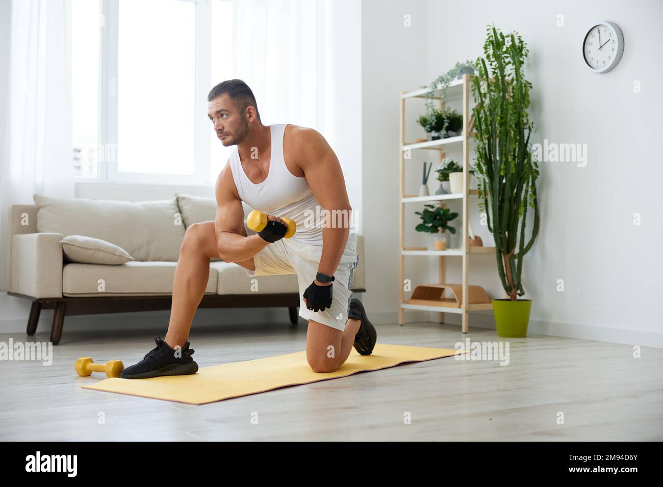 Man sports home training on the floor on a mat with dumbbells ...