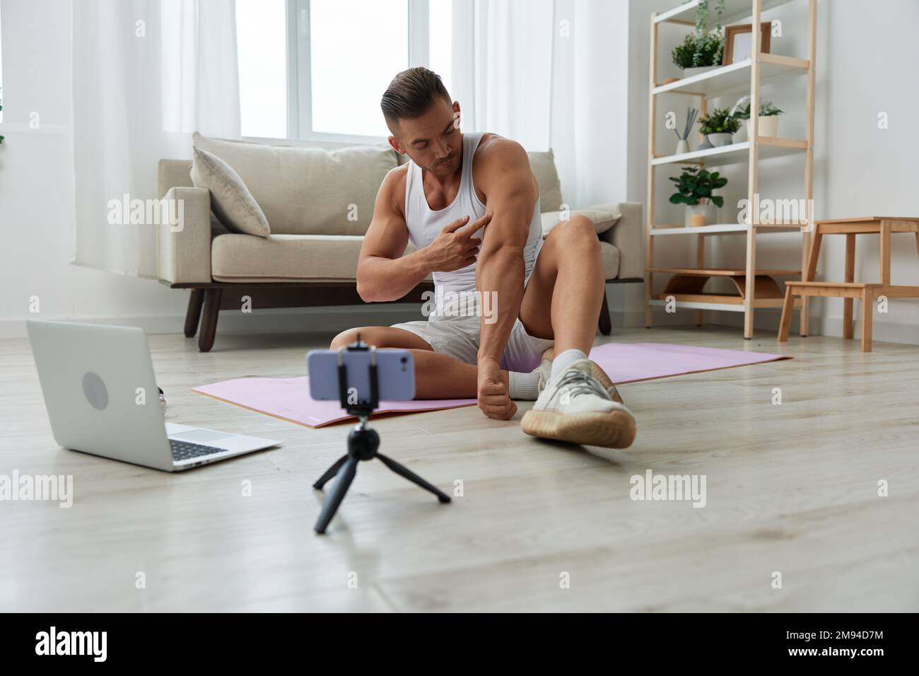 Man Sports Watching Tape Of Workout On Phone And Repeating Exercises