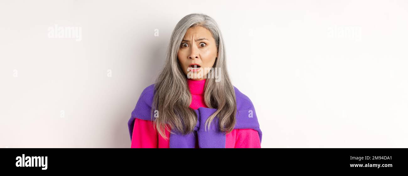 Close-up of shocked asian senior woman gasping, staring with confused ...