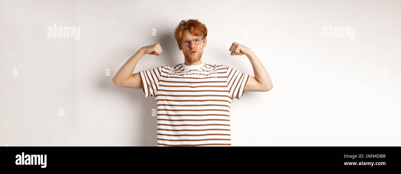 Image of confident and strong redhead man flexing biceps, showing ...