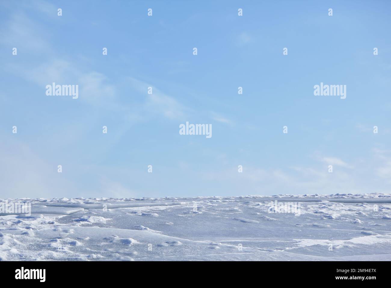 Winter ice landscape under blue sky and clouds. Cracks in the ice field ...