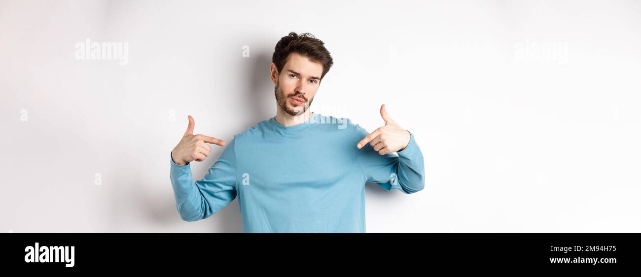 Young man with beard feeling confident, pointing at himself and making ...