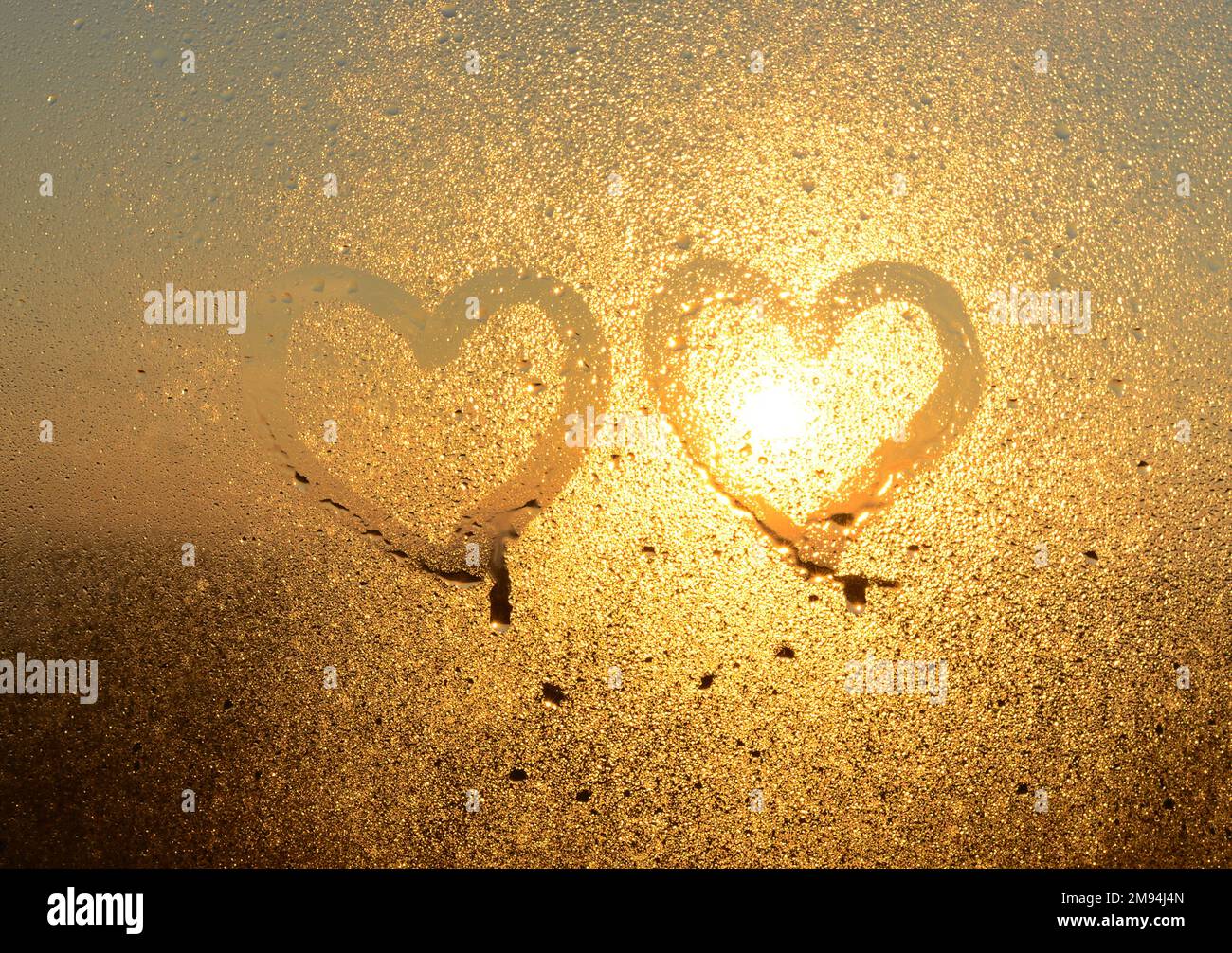 2 lovers hearts drawn with a finger on the fogged window glass ...