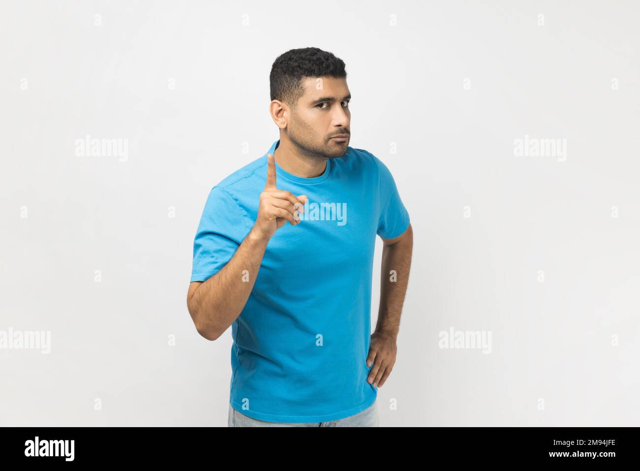 Portrait of serious bossy attractive unshaven man wearing blue T- shirt ...