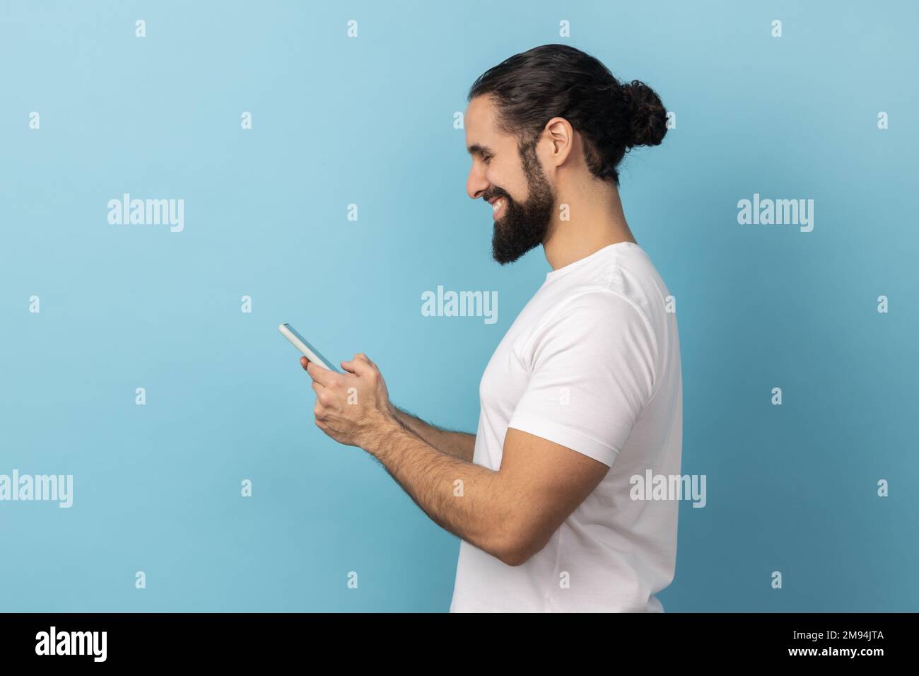 Side view of handsome positive man bodybuilder with beard wearing white ...