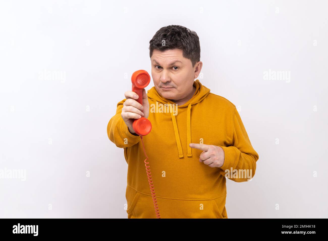 Middle aged man pointing finger at handset of red vintage landline ...