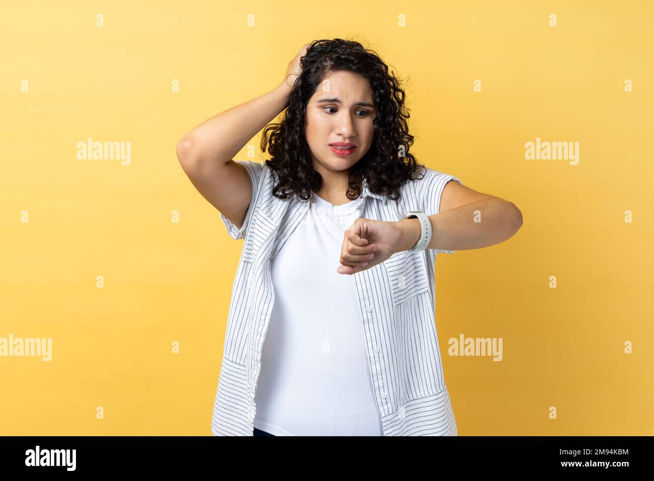 Portrait of woman with dark wavy hair standing with puzzled facial ...