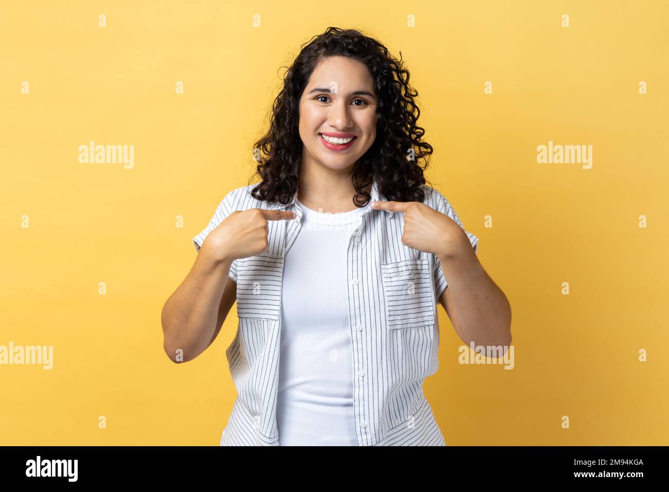 Portrait of friendly woman with dark wavy hair pointing finger at ...