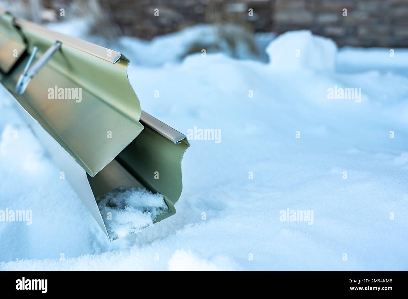 Section of new metal gutters laying on the ground with snow ready for ...