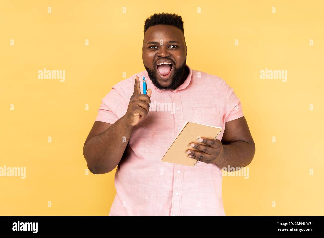 Portrait of happy man wearing pink shirt writing creative idea into ...