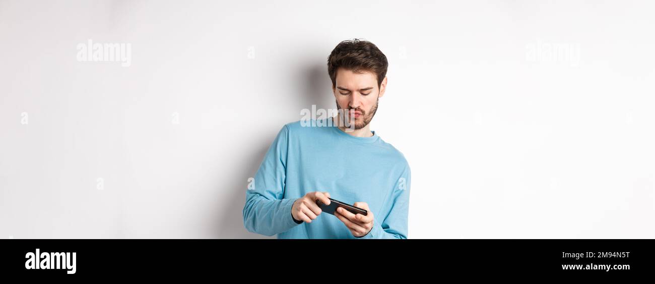 Young man playing video games on smartphone, tilt body and tap mobile ...