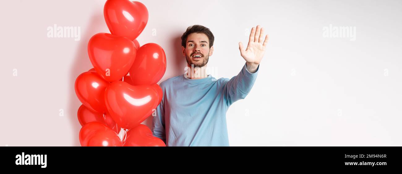 Handsome young caucasian man standing with romantic heart balloon and ...