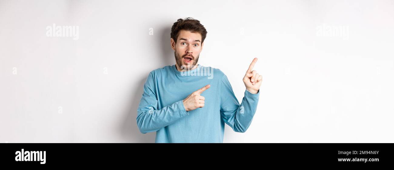 Amazed man showing awesome promo offer, pointing fingers at upper left ...