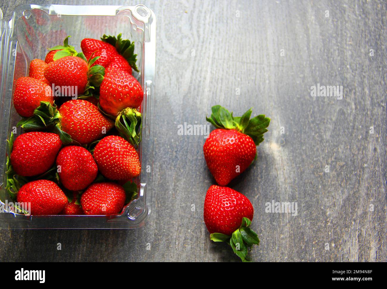 Select fruit, red strawberries in plastic packaging, vintage gray wood ...