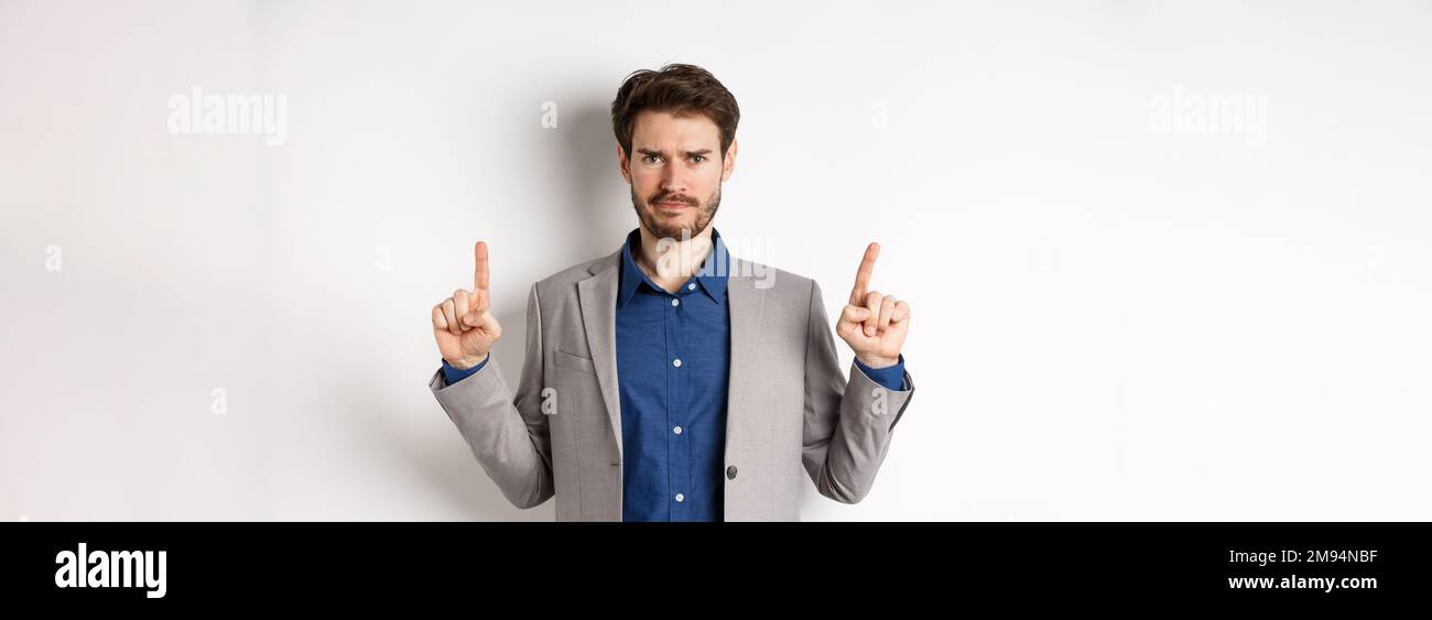 Disappointed male entrepreneur frowning, pointing fingers up and look ...
